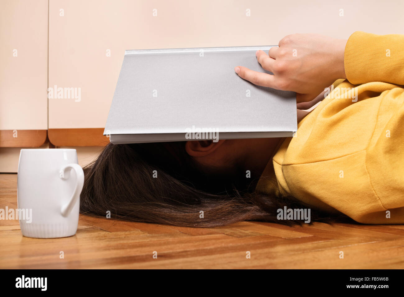 Late night study. Young girl lying on the floor in her room with a book ...
