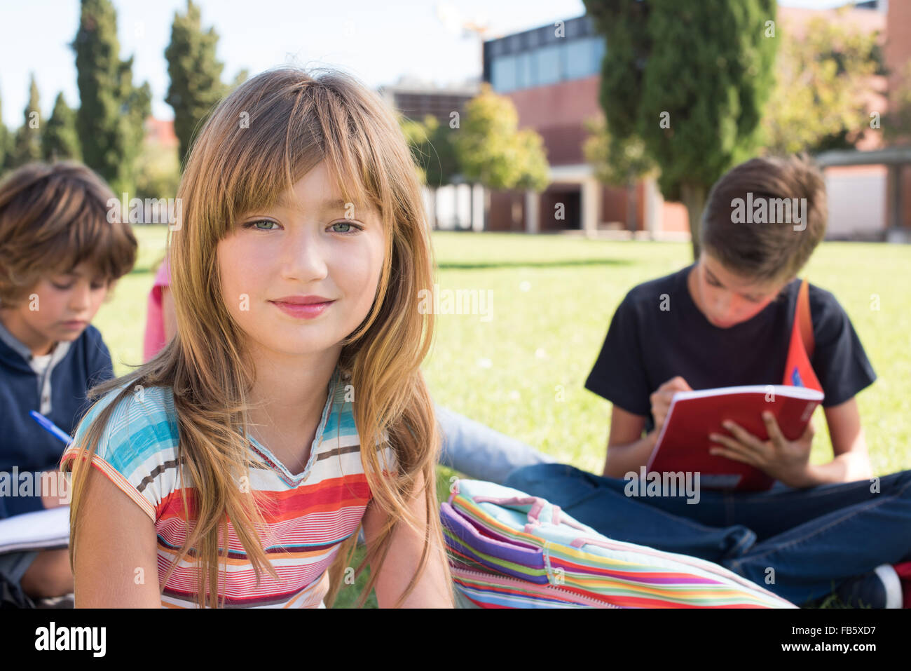 Group of little students sitting on the grass at school Stock Photo - Alamy
