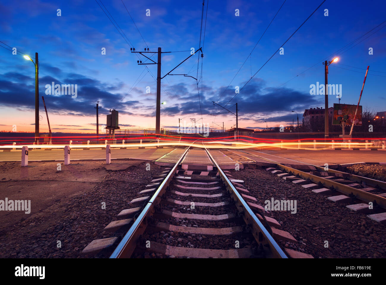 Railroad crossing with car lights in motion at night Stock Photo - Alamy
