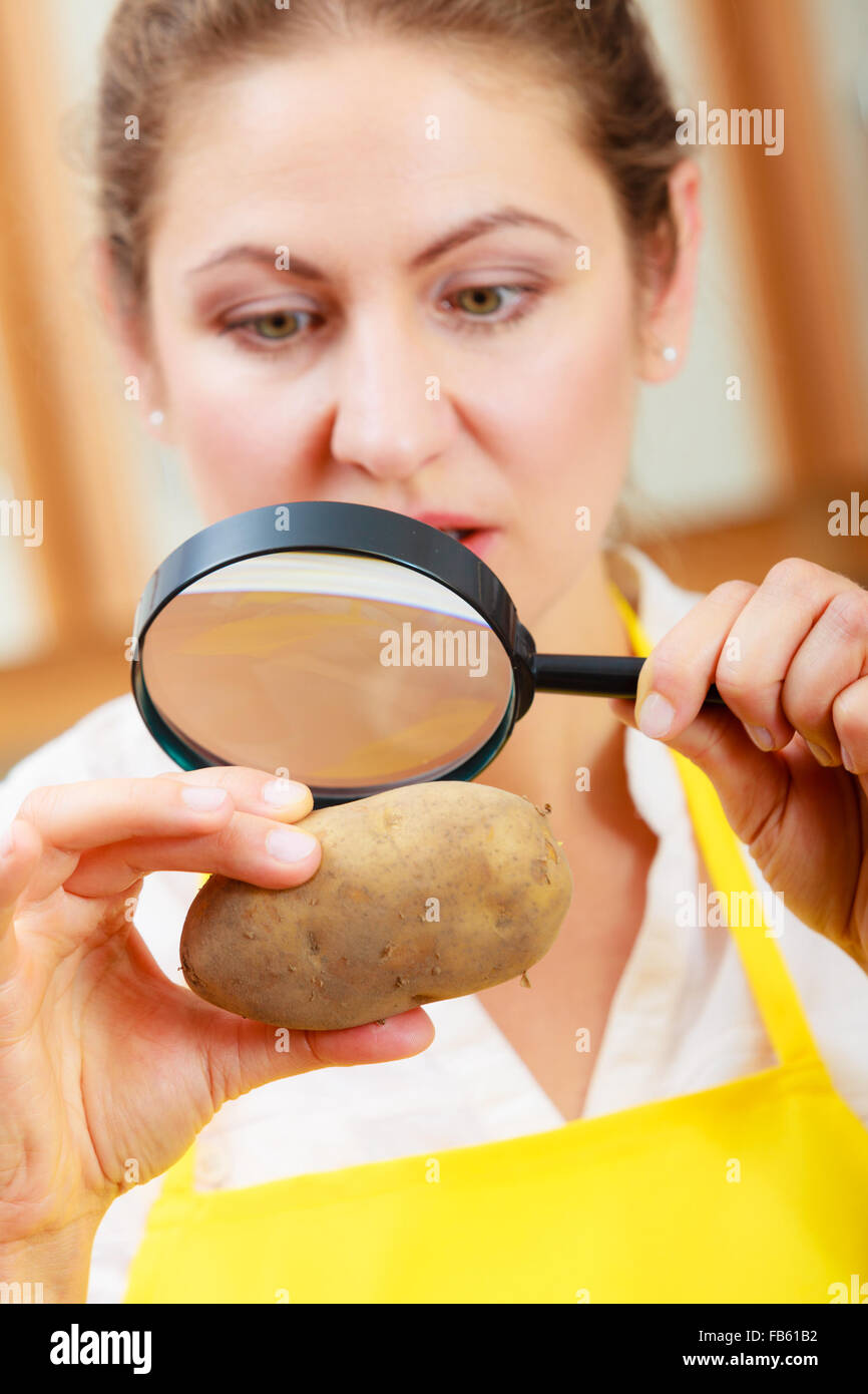 Mature woman female inspecting testing potato food with magnifying ...