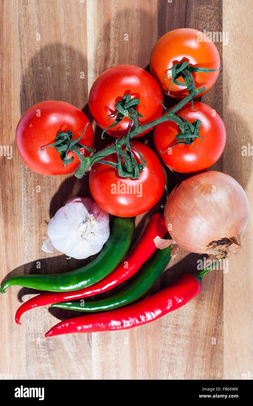 Five vine tomatoes, garlic bulb, one onion and four chillies on a ...