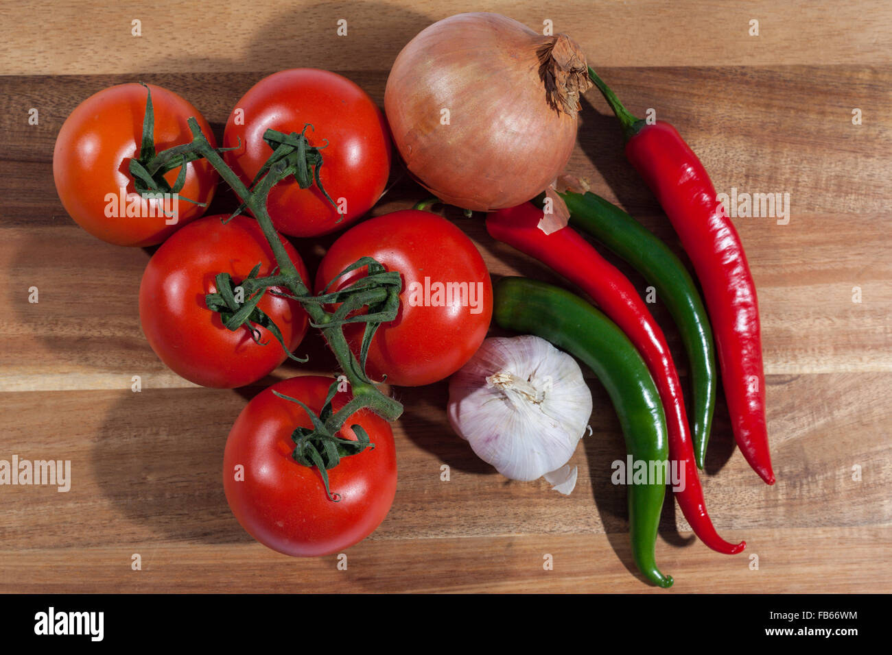 Five vine tomatoes, garlic bulb, one onion and four chillies on a ...