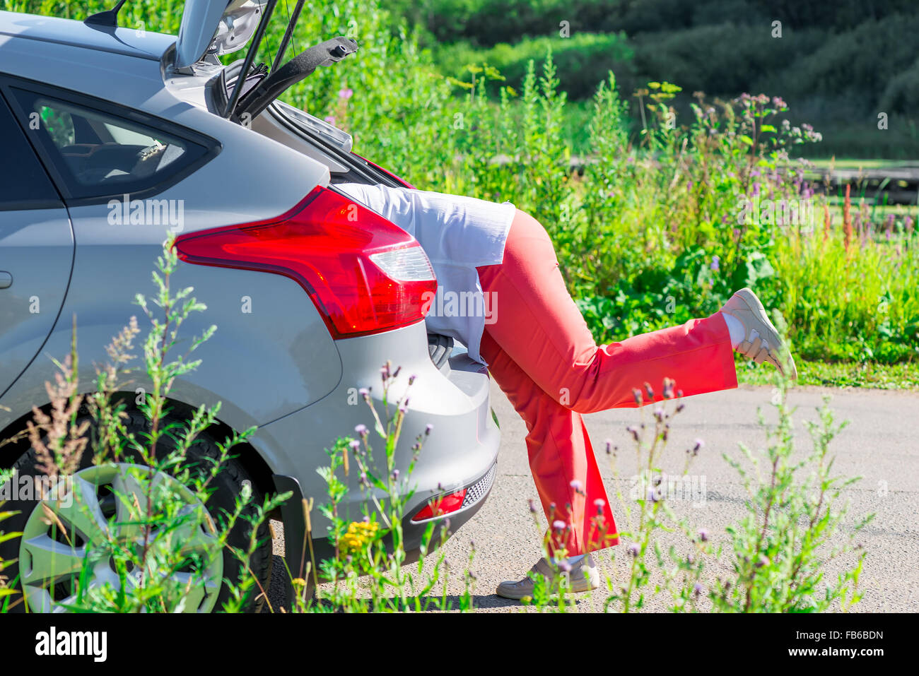Women's legs sticking out of the trunk of the car on the road Stock ...