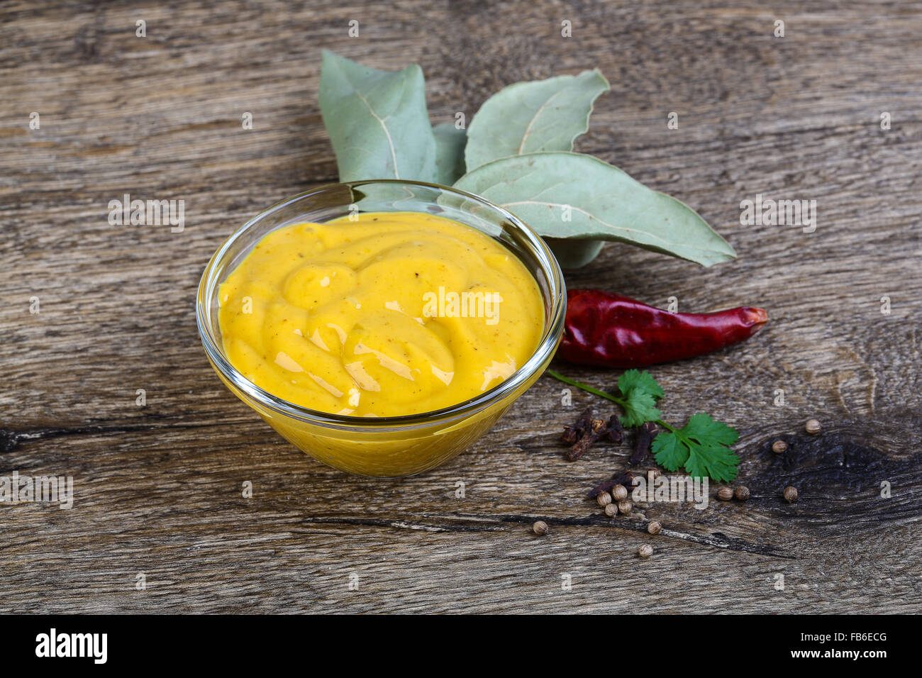 Curry sause with red pepper and coriander seeds on wood background ...