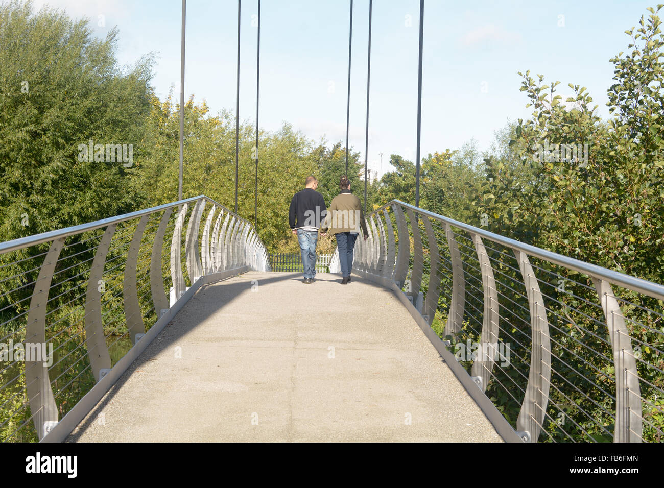 Couple holding hands crossing the new suspension bridge over the River ...
