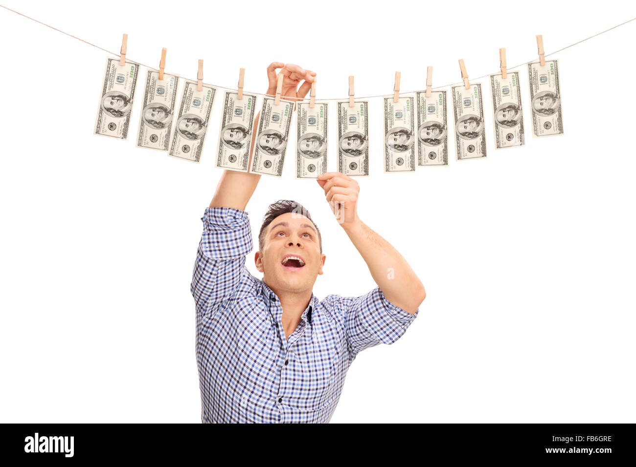 Studio shot of a happy young man pinning money on a clothesline and ...