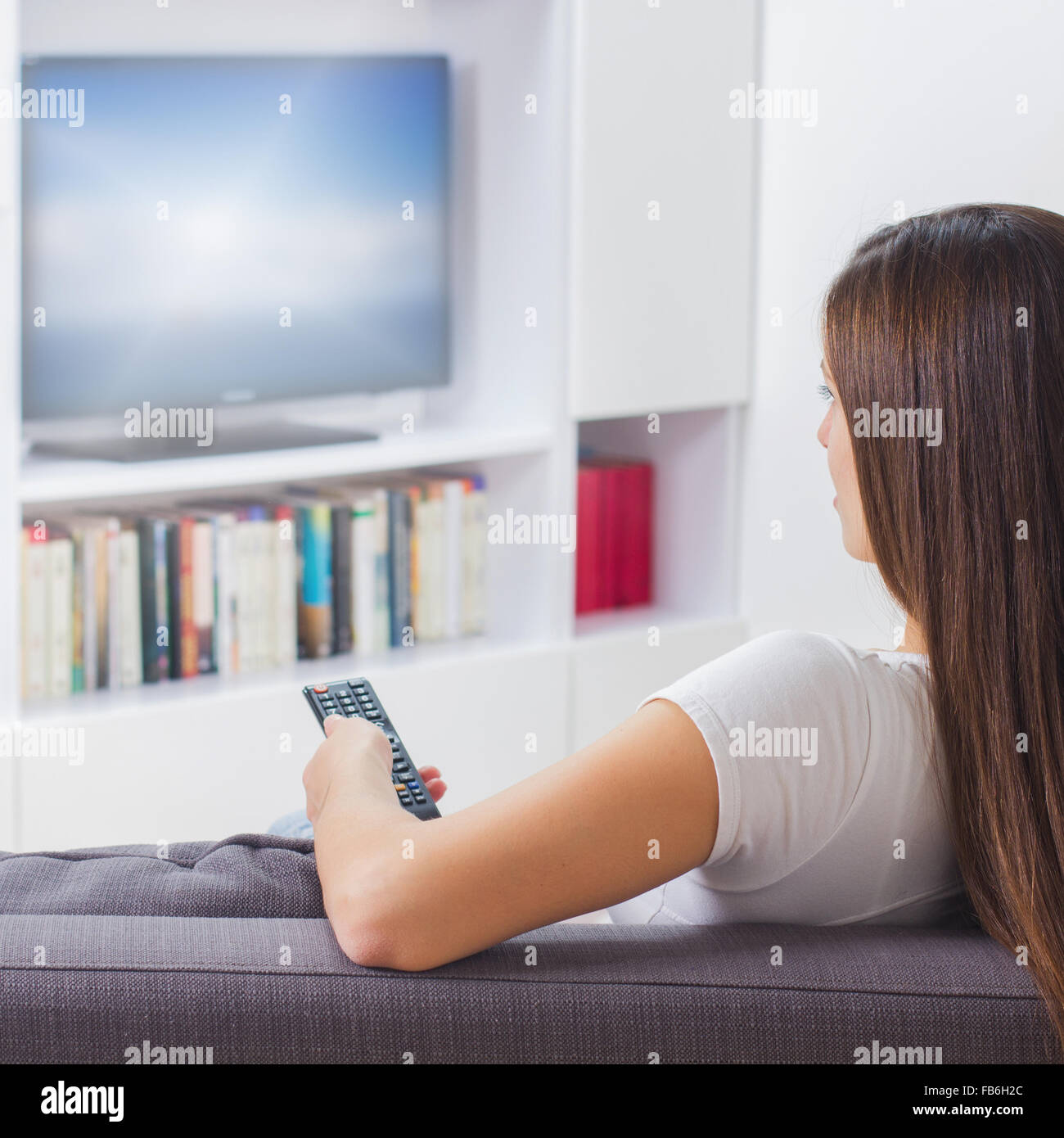 Young woman with remote control, watching TV program at home, Photo on ...