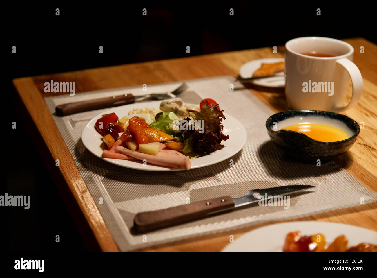 Served dinner with ham, greens, cup and desert on a table with soft ...