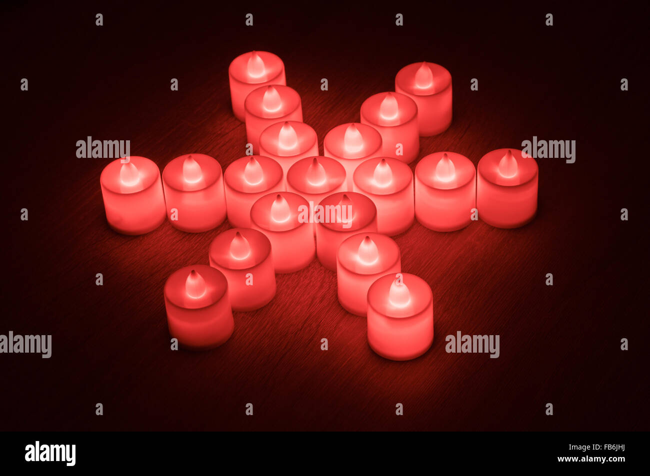 Snowflake symbol made from red led candles on wooden background ...