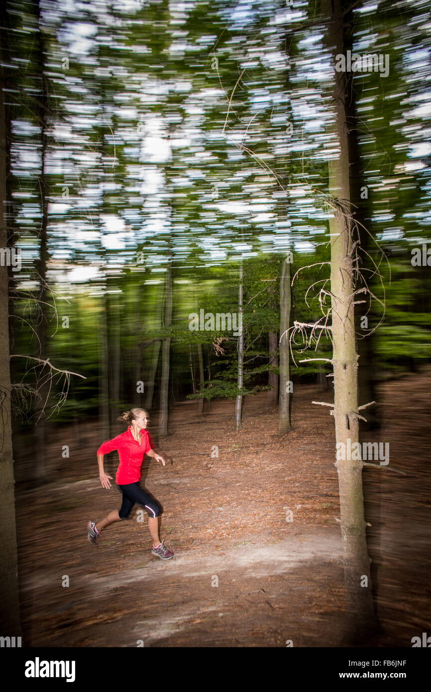 Young woman running outdoors in a forest, going fast (motion blurred ...