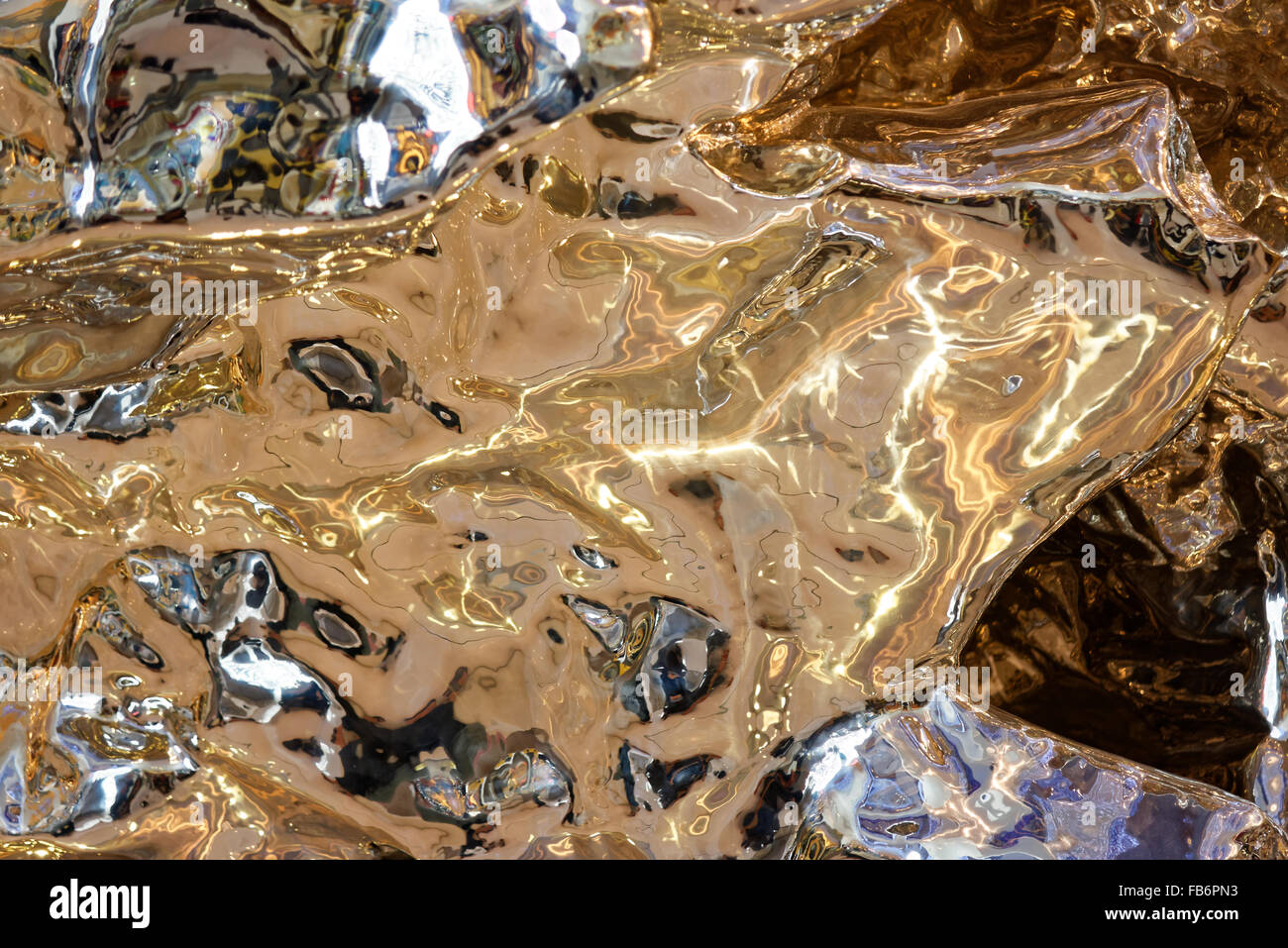 liquid metal reflective sculpture closeup in a warm light Stock Photo ...