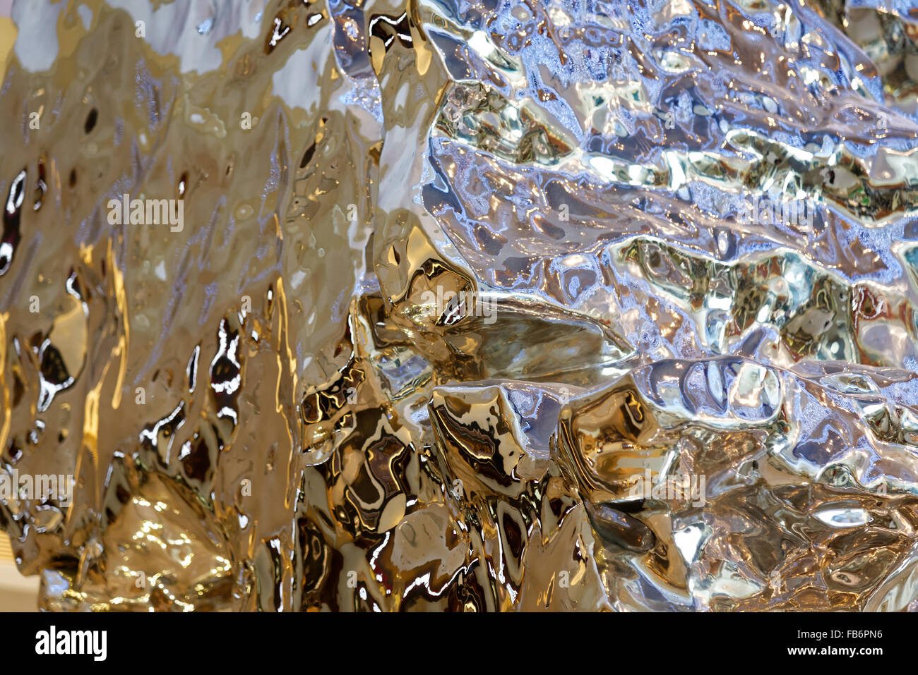 liquid metal reflective sculpture closeup in a warm light Stock Photo ...