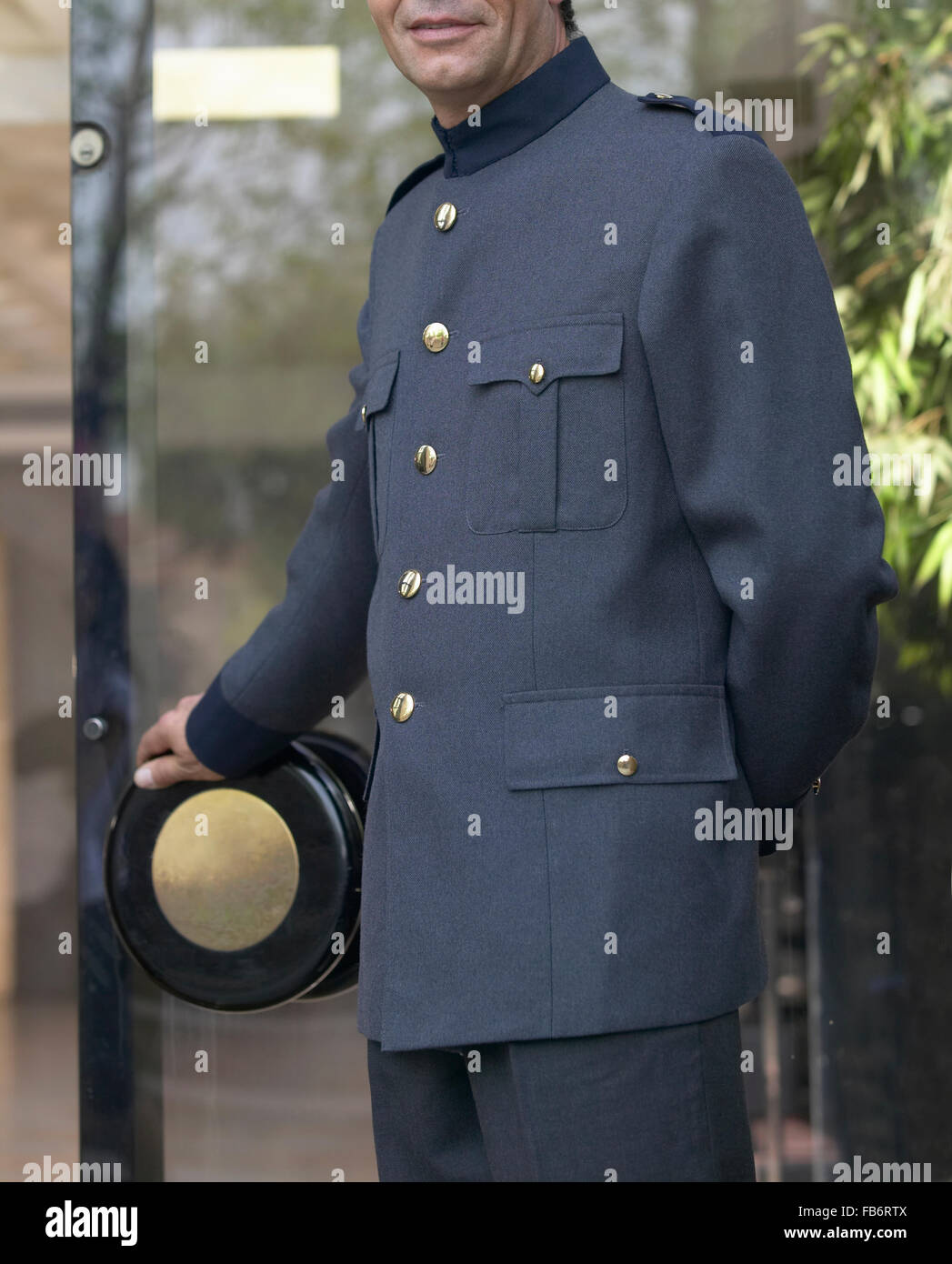 Smiley Bellhop with grey uniform opening Hotel´s door Stock Photo - Alamy