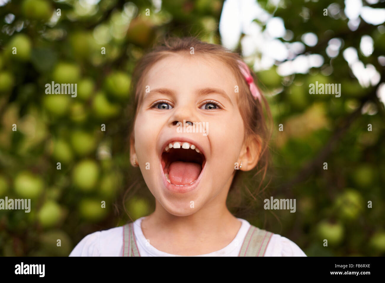 Portrait of a cute little girl making an excited face with her mouth ...