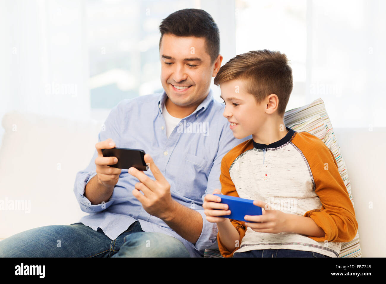 happy father and son with smartphones at home Stock Photo - Alamy