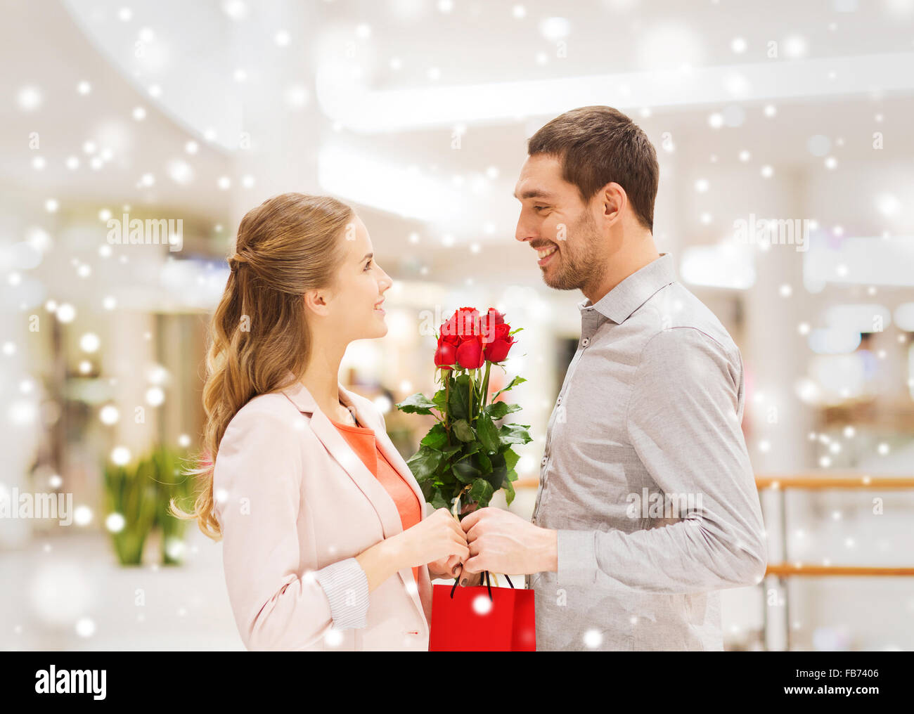 man giving woman red roses and present in mall Stock Photo - Alamy