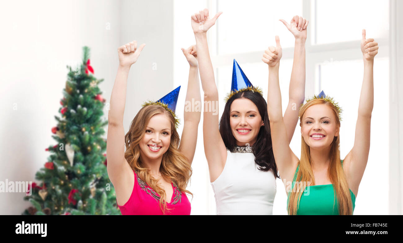 smiling women in party caps showing thumbs up Stock Photo - Alamy