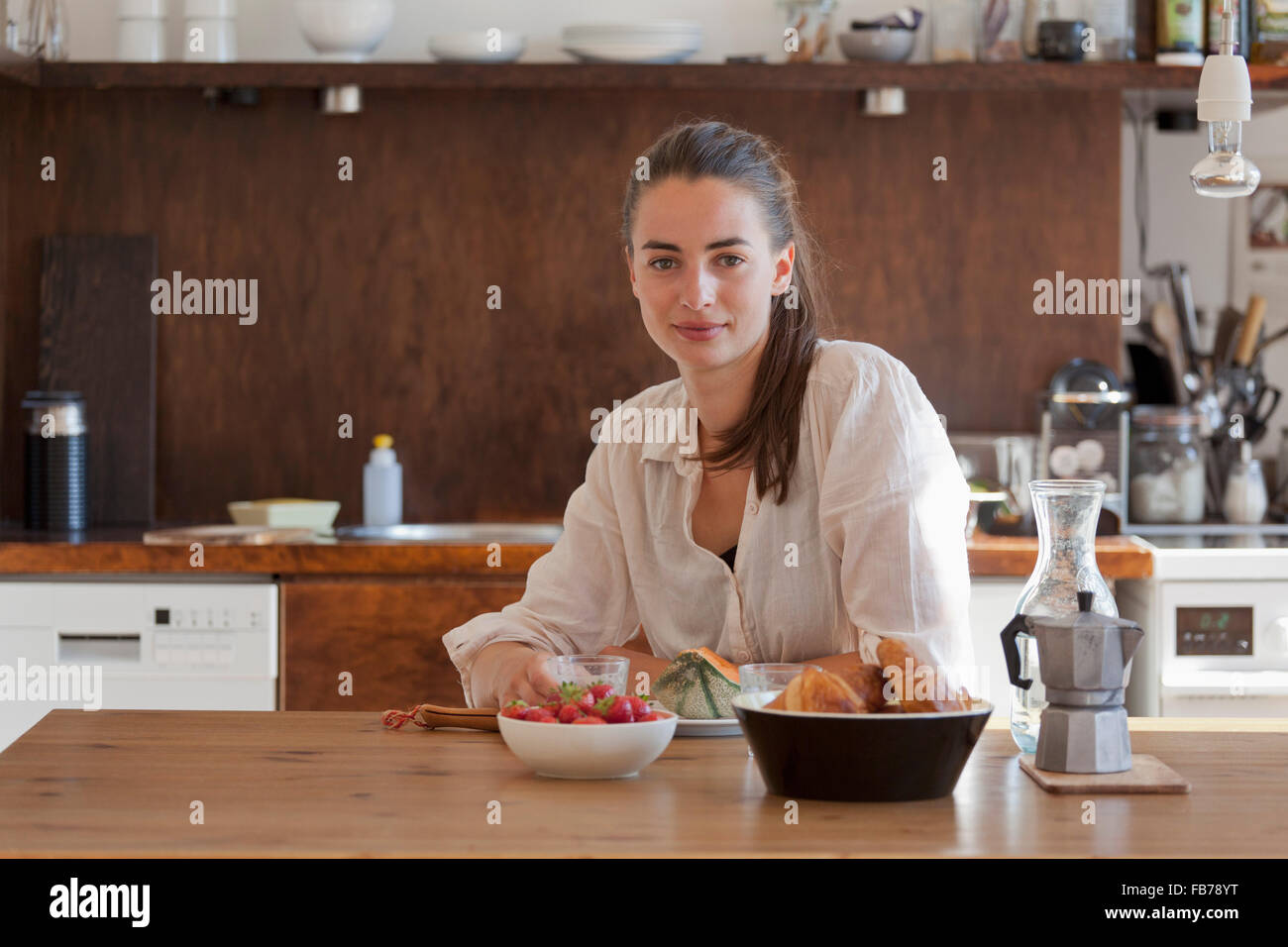 Young woman sitting at dining table, portrait Stock Photo - Alamy