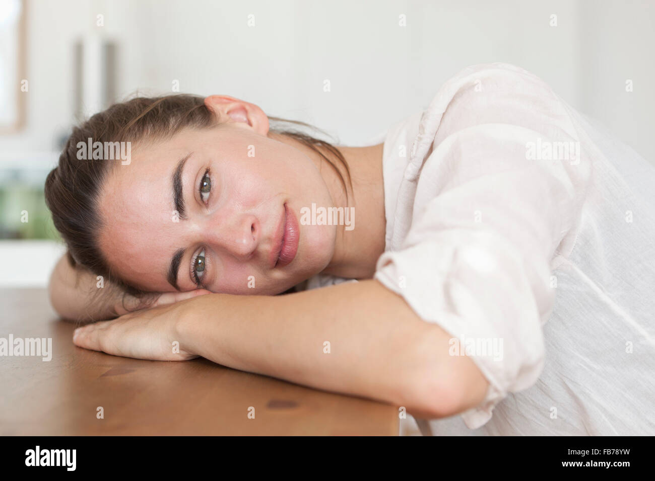 Young woman leaning on table, portrait Stock Photo - Alamy