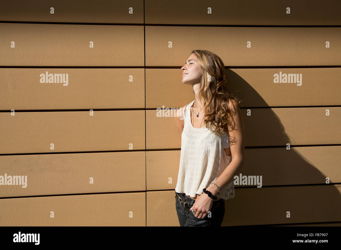 Young woman leaning on wall Stock Photo - Alamy