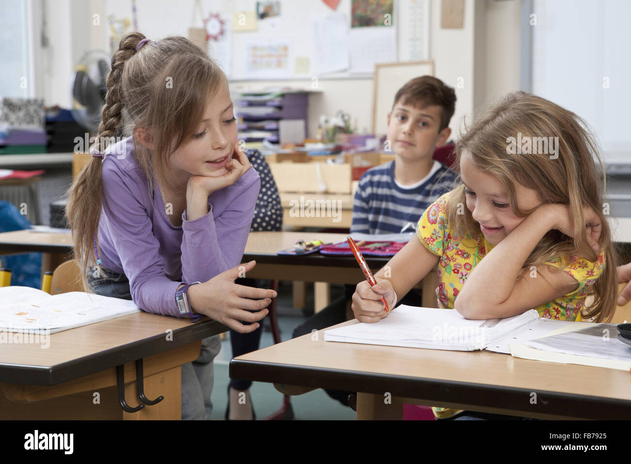 Students writing on book in classroom Stock Photo - Alamy