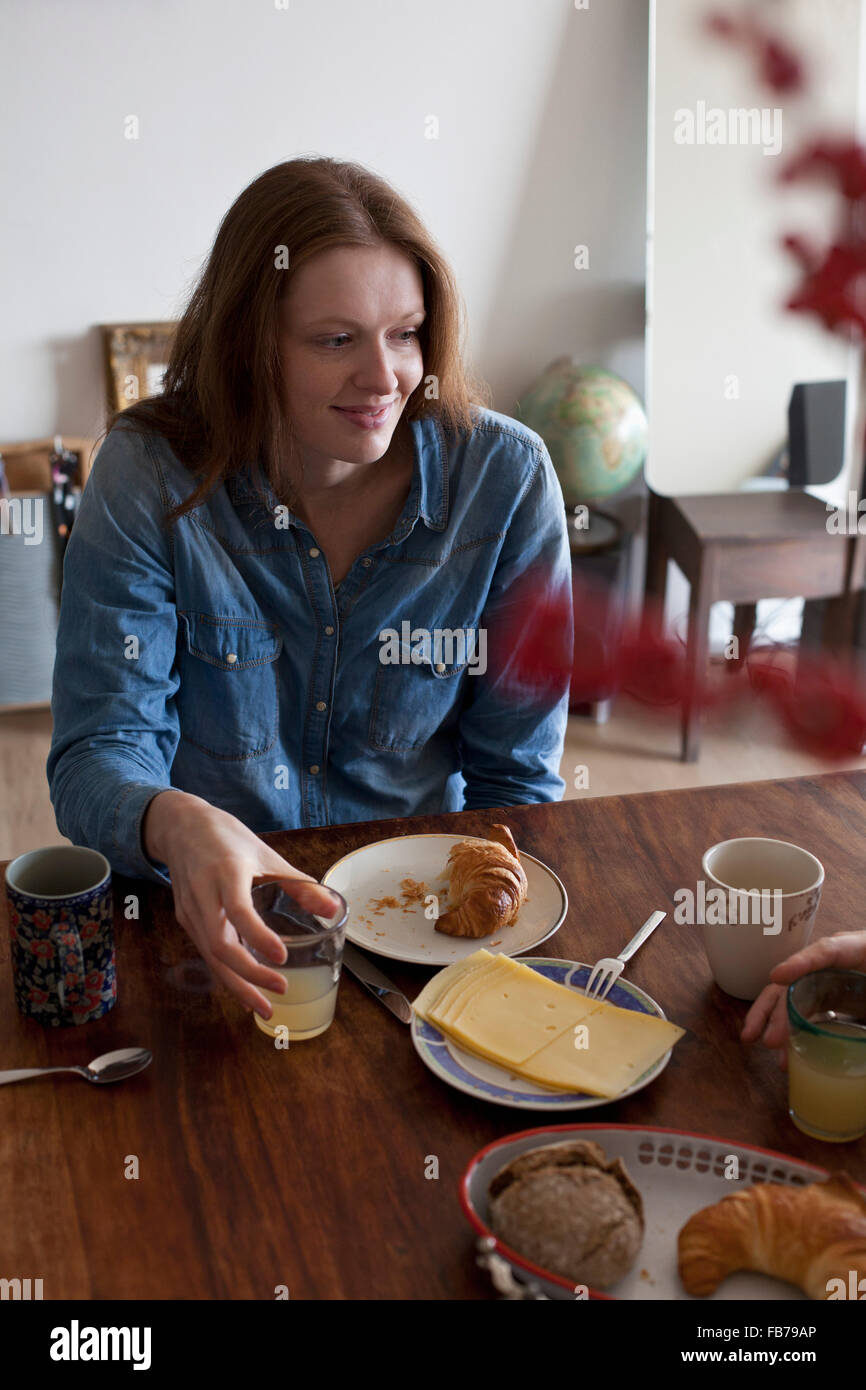 Woman having breakfast at dining table Stock Photo - Alamy
