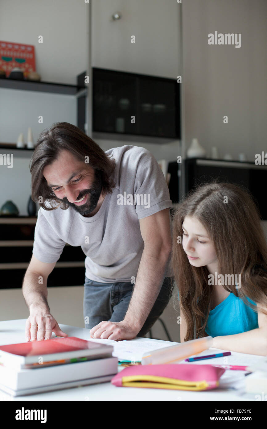 Smiling father assisting daughter in doing homework at table Stock Photo - Alamy