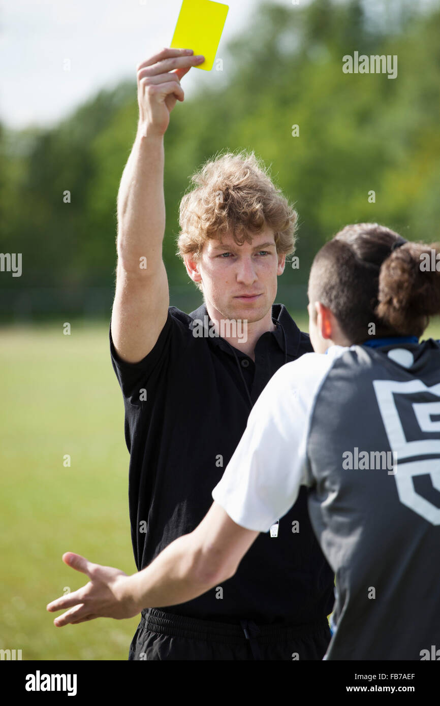 Referee showing yellow card to soccer player Stock Photo - Alamy