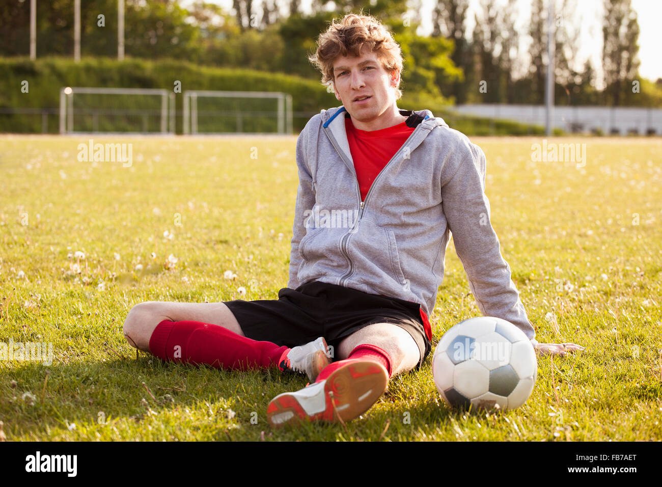 Portrait of young soccer player resting on field Stock Photo - Alamy
