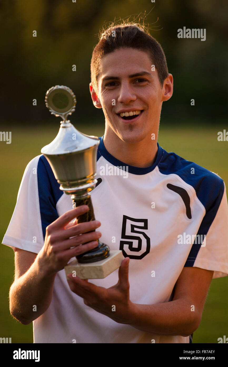 Portrait of happy soccer player holding trophy Stock Photo - Alamy