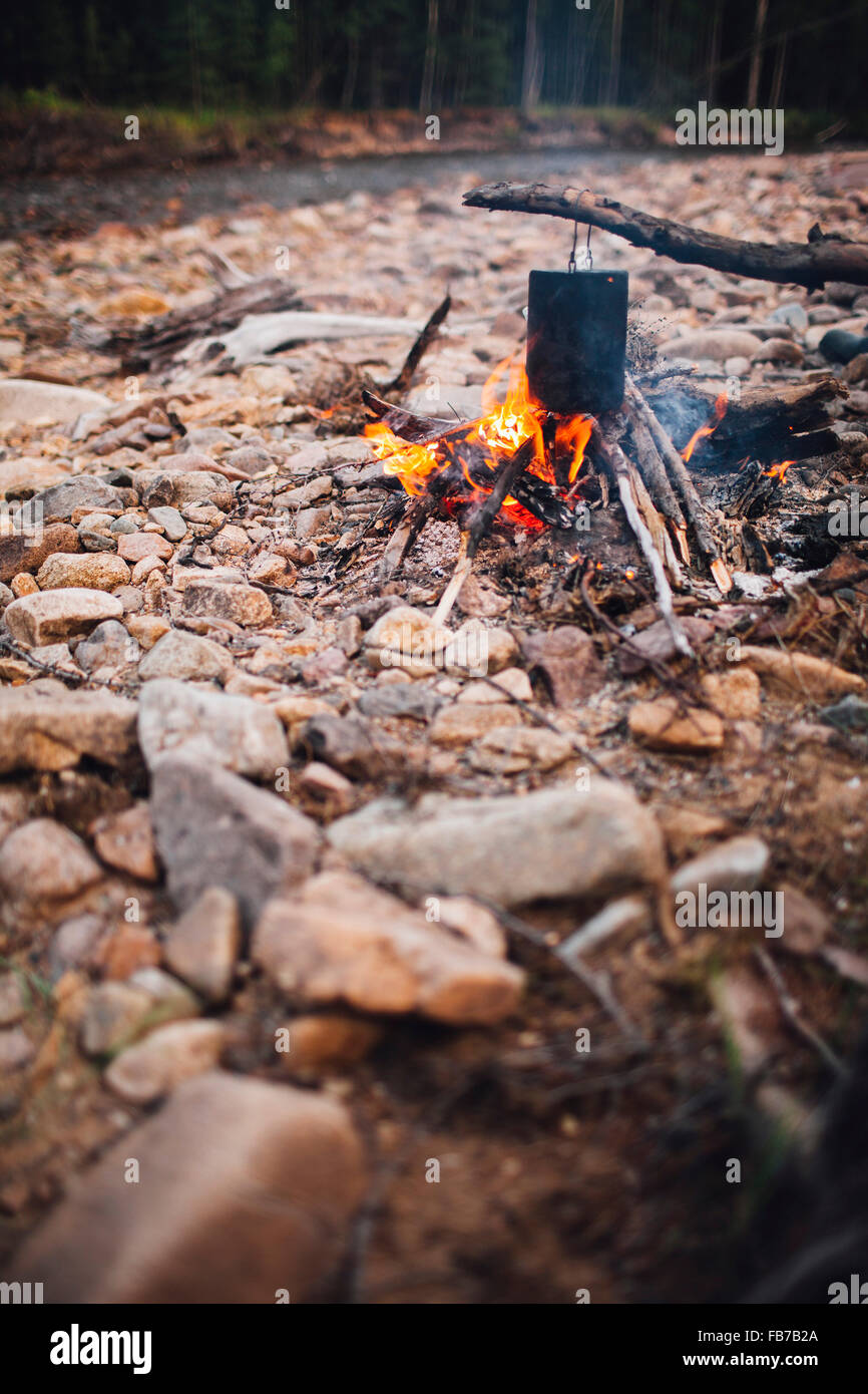 Container hanging over campfire in forest Stock Photo - Alamy