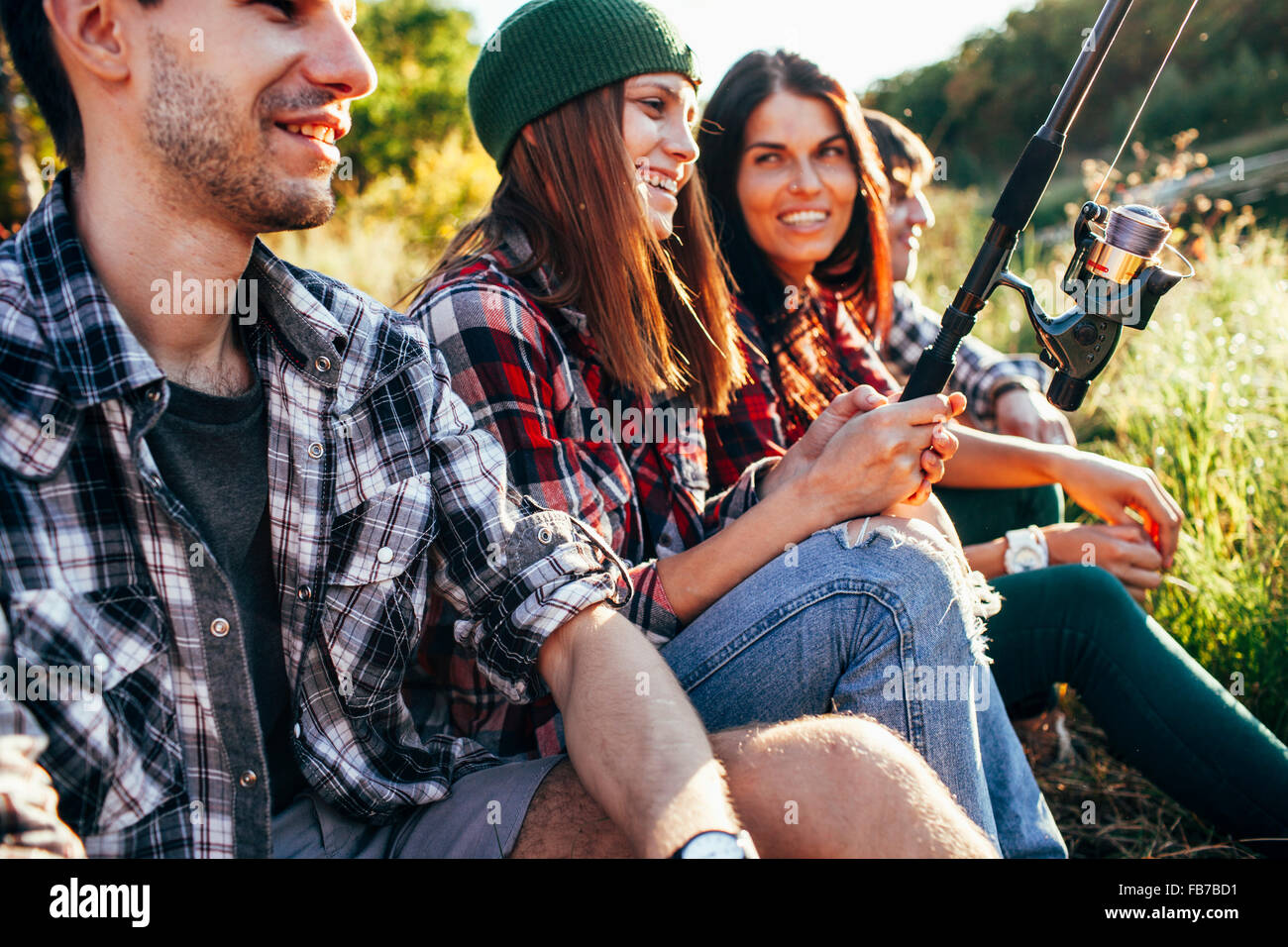 Happy friends fishing together in forest Stock Photo - Alamy