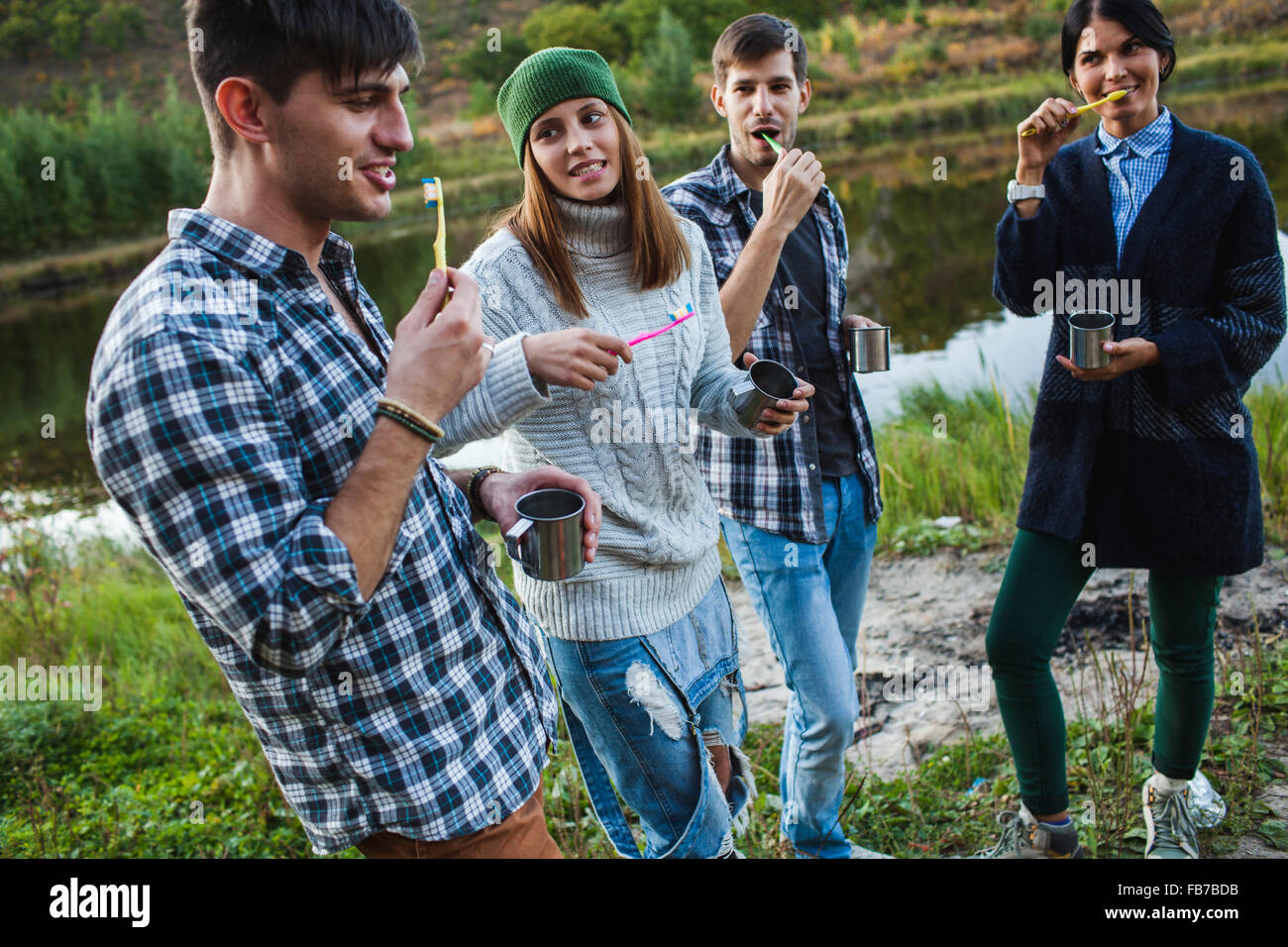 Friends brushing teeth at lakeshore in forest Stock Photo - Alamy