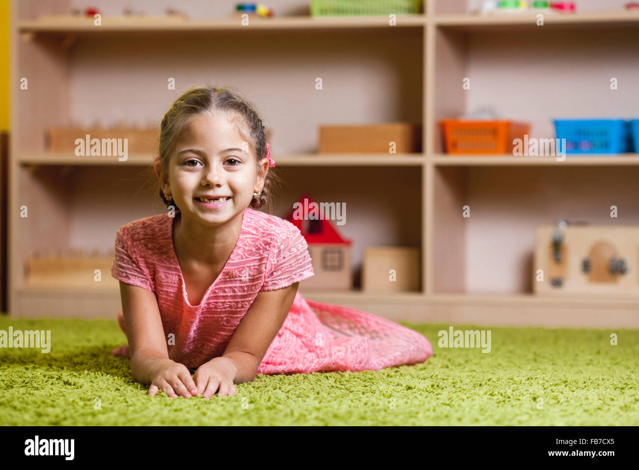 Portrait of happy girl lying on rug in classroom Stock Photo - Alamy