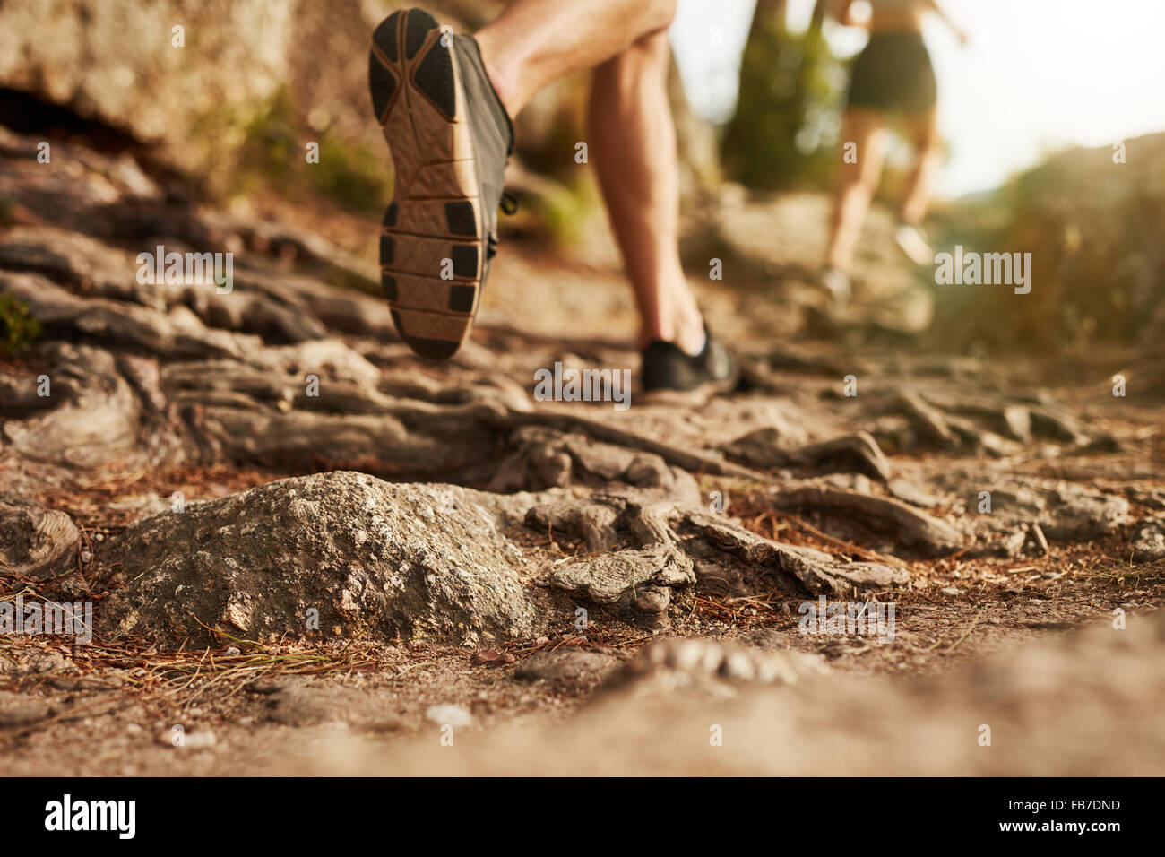 Cross country running. Closeup of male feet run through rocky terrain ...