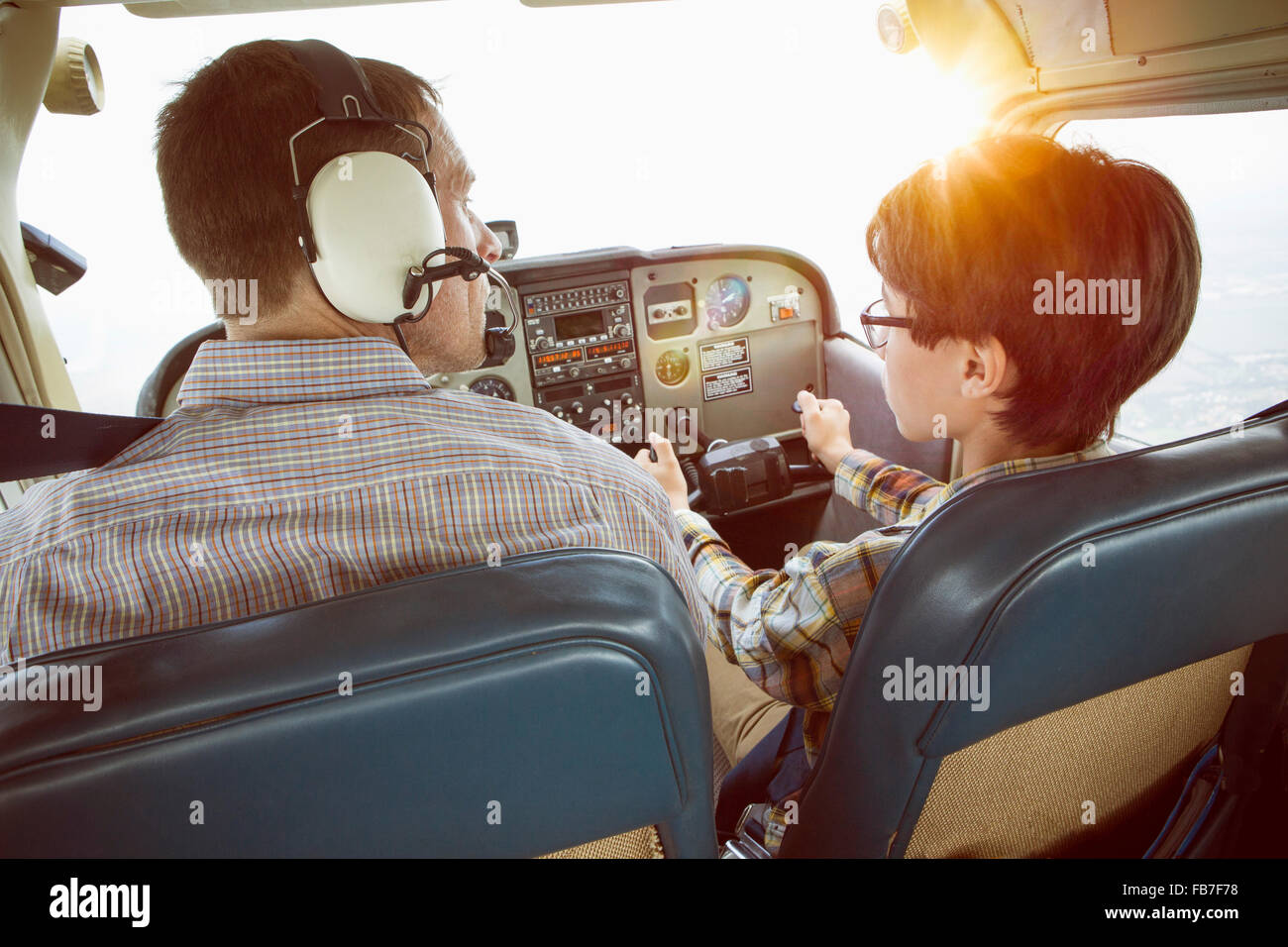 Rear view of father and son in cockpit of private airplane Stock Photo ...
