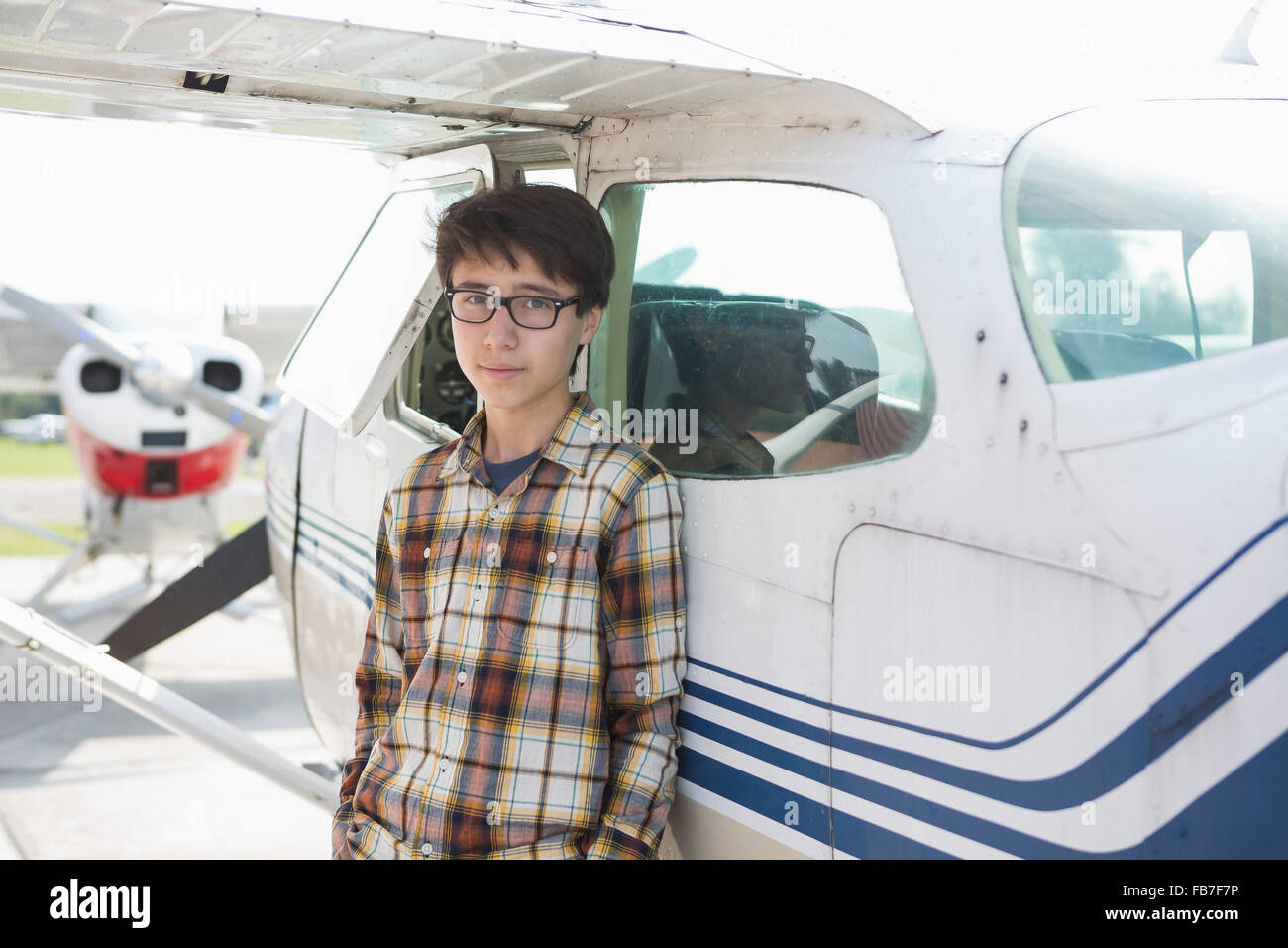 Portrait of confident teenage boy standing outside private airplane ...