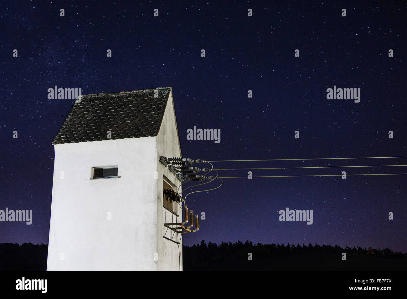 Low angle view of power cables attached to building against starry sky ...