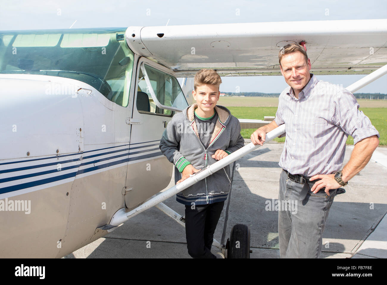 Portrait of happy father and son standing outside private airplane ...