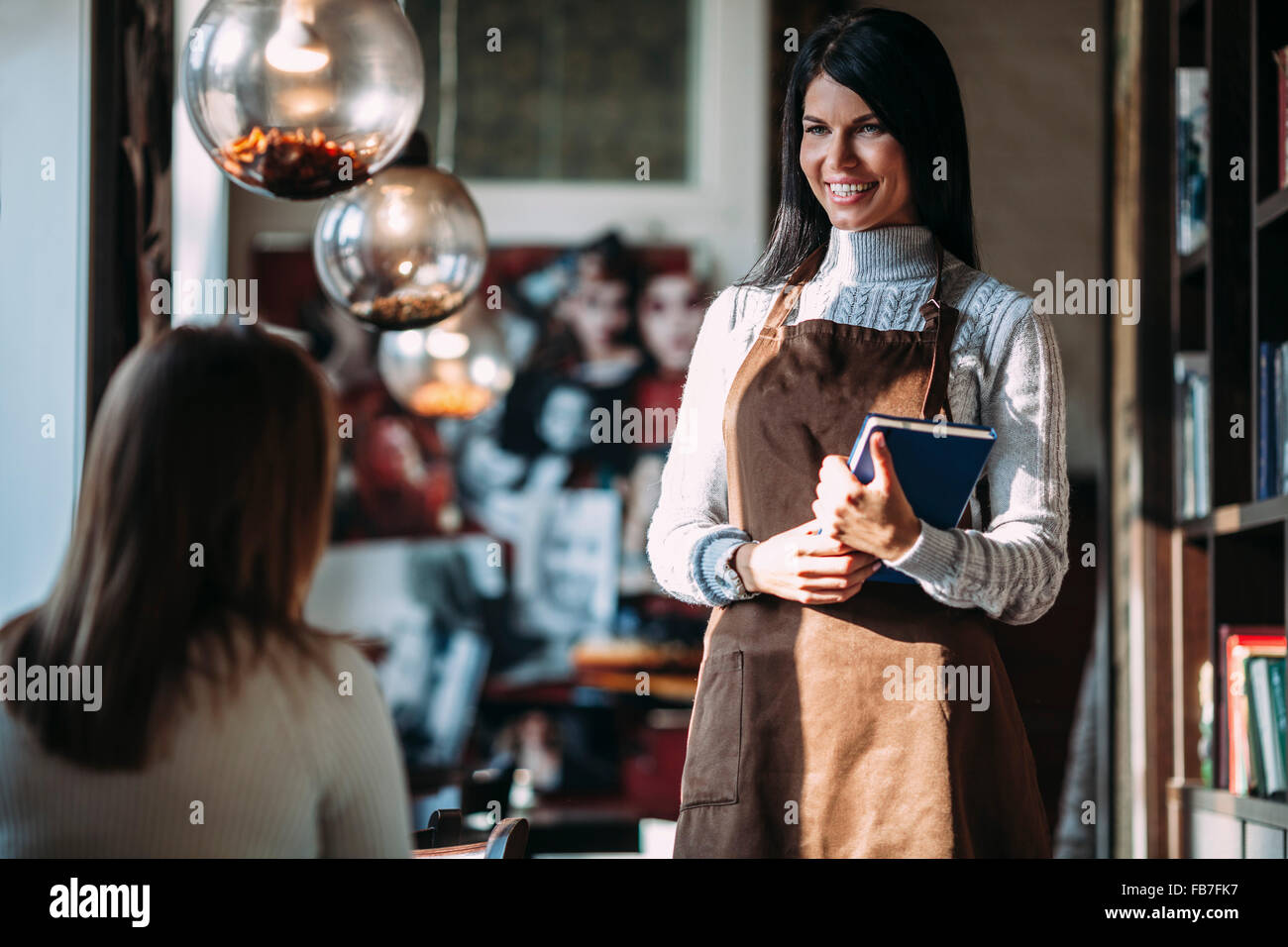Happy waitress talking to female customer in coffee shop Stock Photo ...