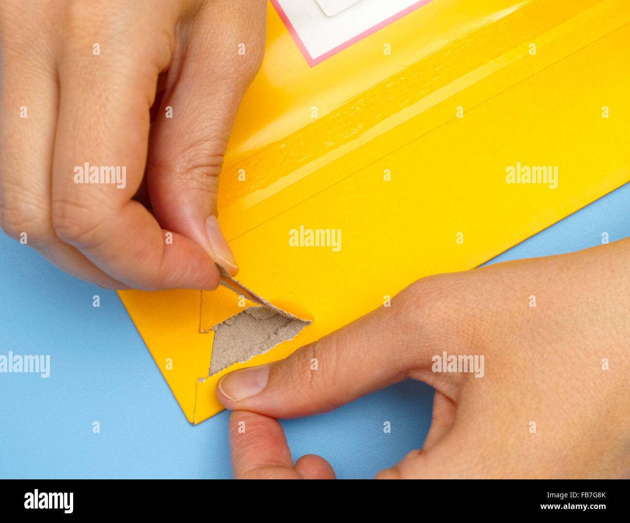 Woman hands opening mail package with easy open strip Stock Photo - Alamy