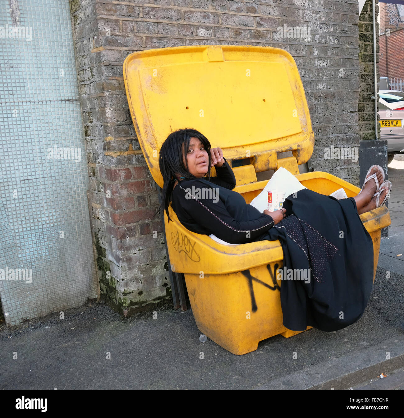 Woman sitting in a rubbish bin on the street in Streets of Brixton ...