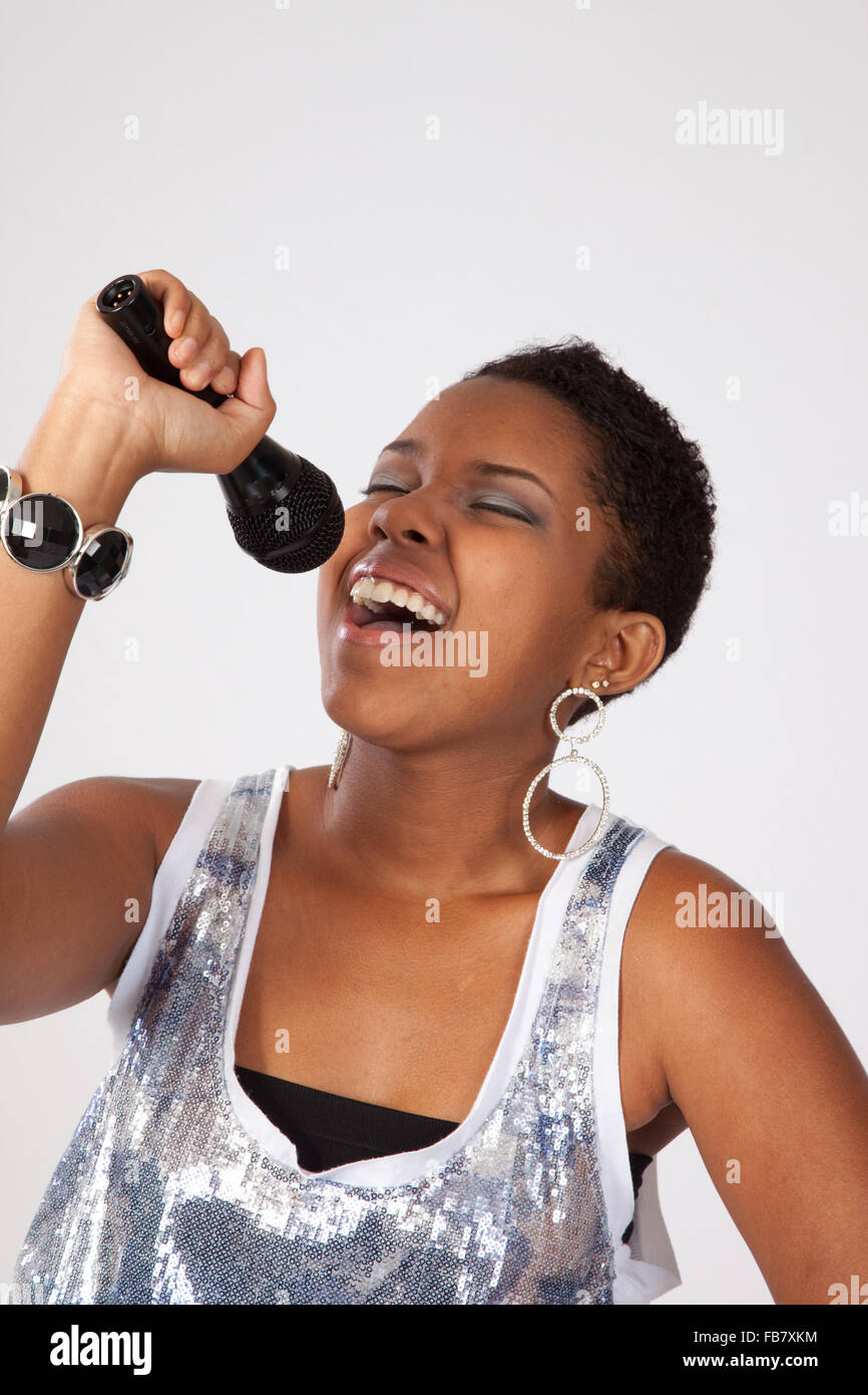Pretty black woman with a microphone, singing with a smile Stock Photo ...