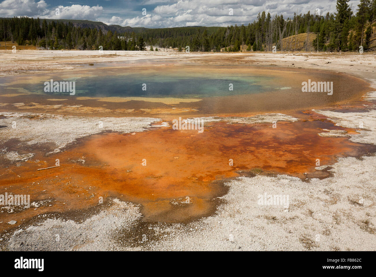 Colorful orange water at Chromatic Pool hot springs under a sunny blue ...