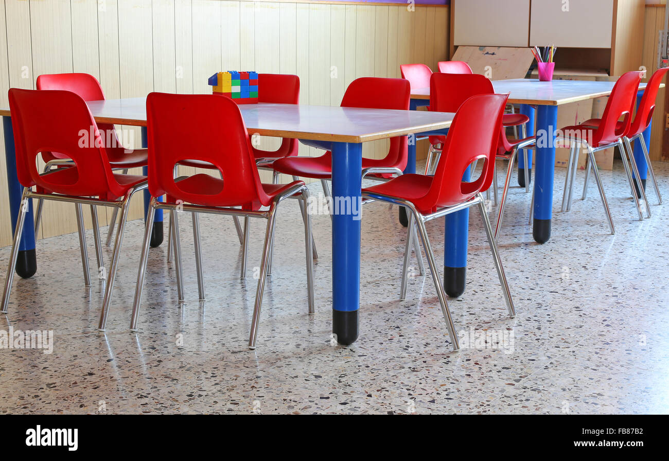 classroom of a kindergarten with red chairs and small school tables ...