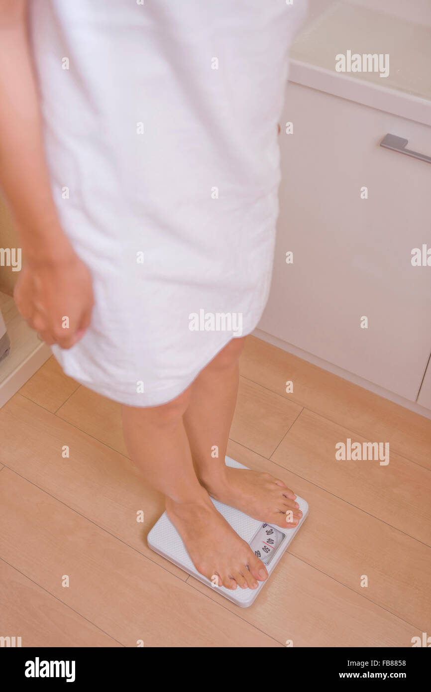 Young woman standing on scale Stock Photo - Alamy