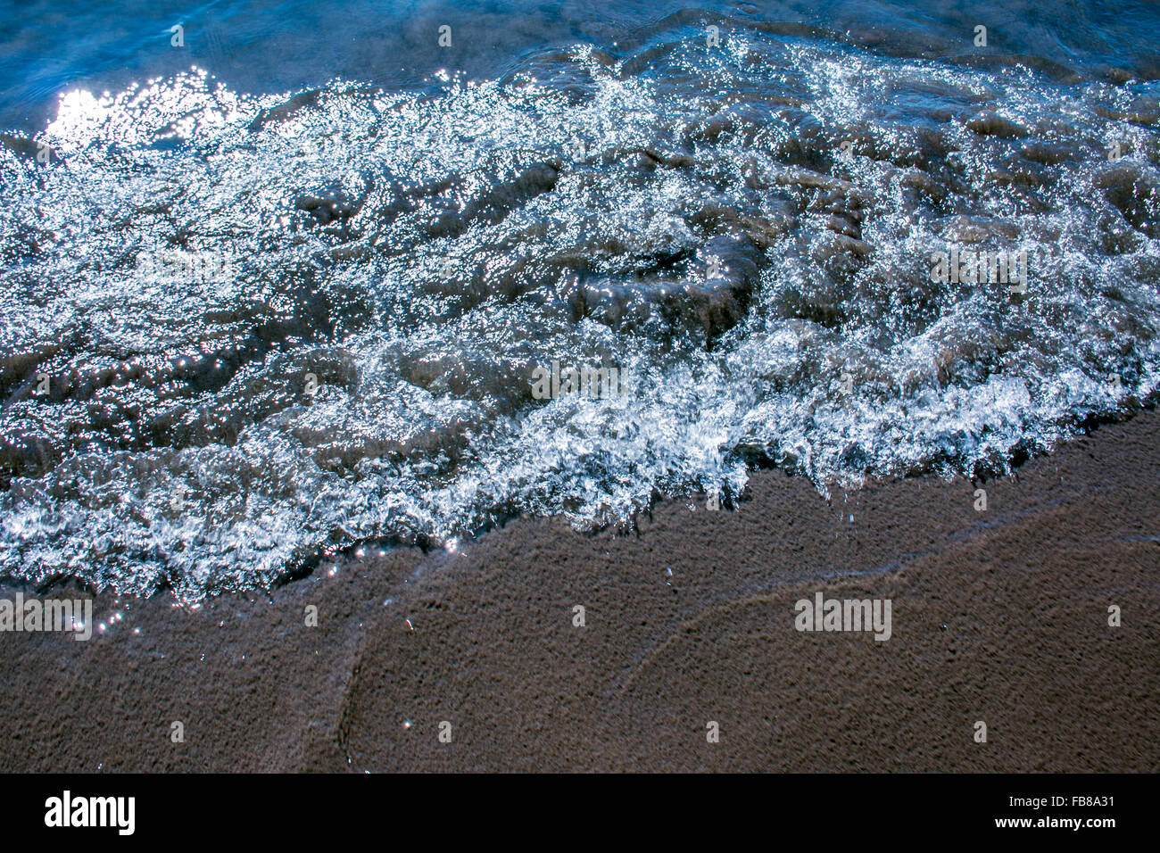 Shiny tropic sea wave on golden beach sand in sunset light Stock Photo ...