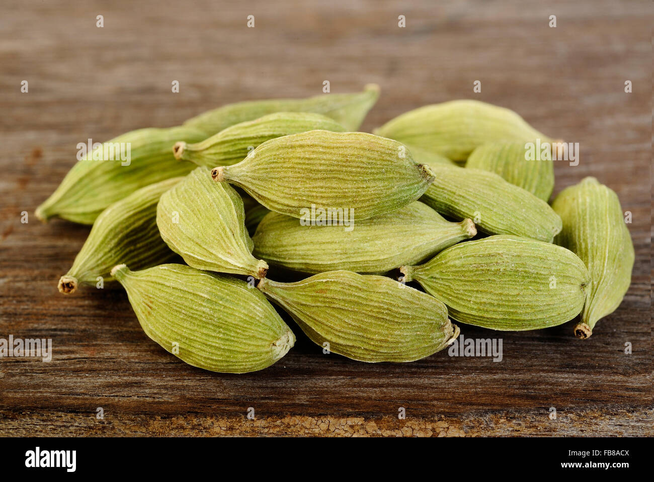 green cardamom pods on wooden background Stock Photo - Alamy