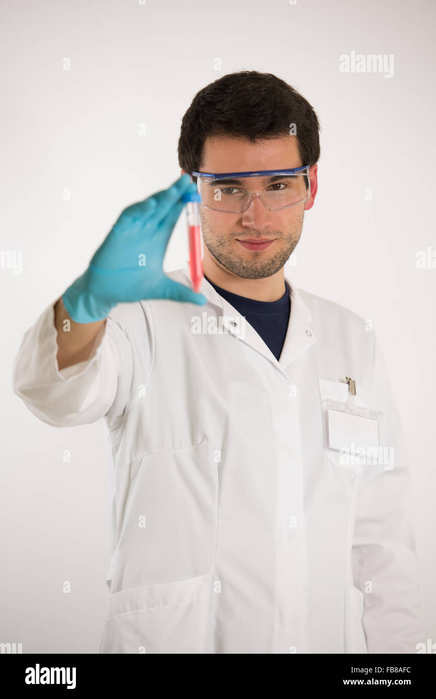 young scientist, wearing white coat and blue gloves, holds tube with ...