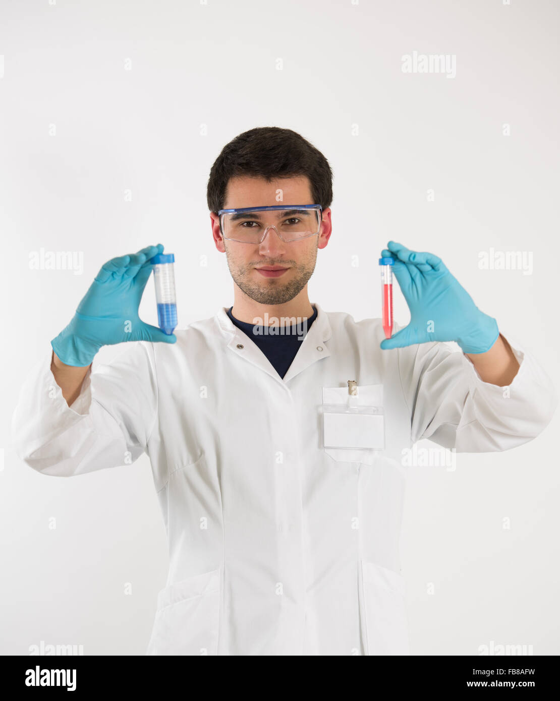 young scientist, wearing white coat and blue gloves, holds tube with ...